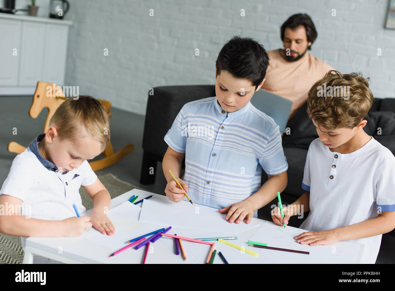 kids drawing pictures with colorful pencils while father using laptop ...