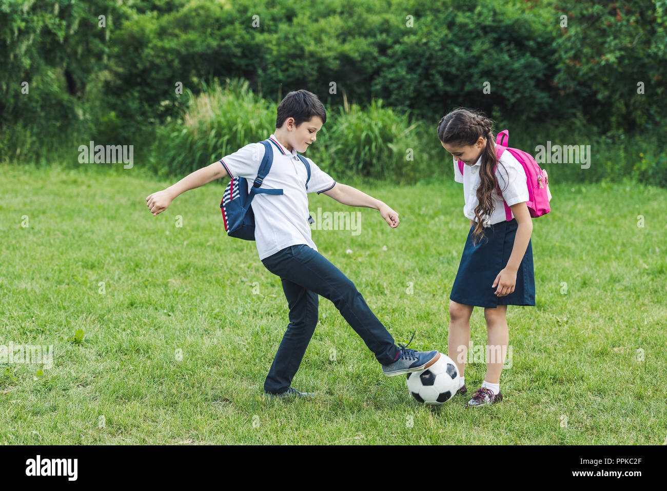happy schoolchildren playing soccer together on meadow in park Stock ...