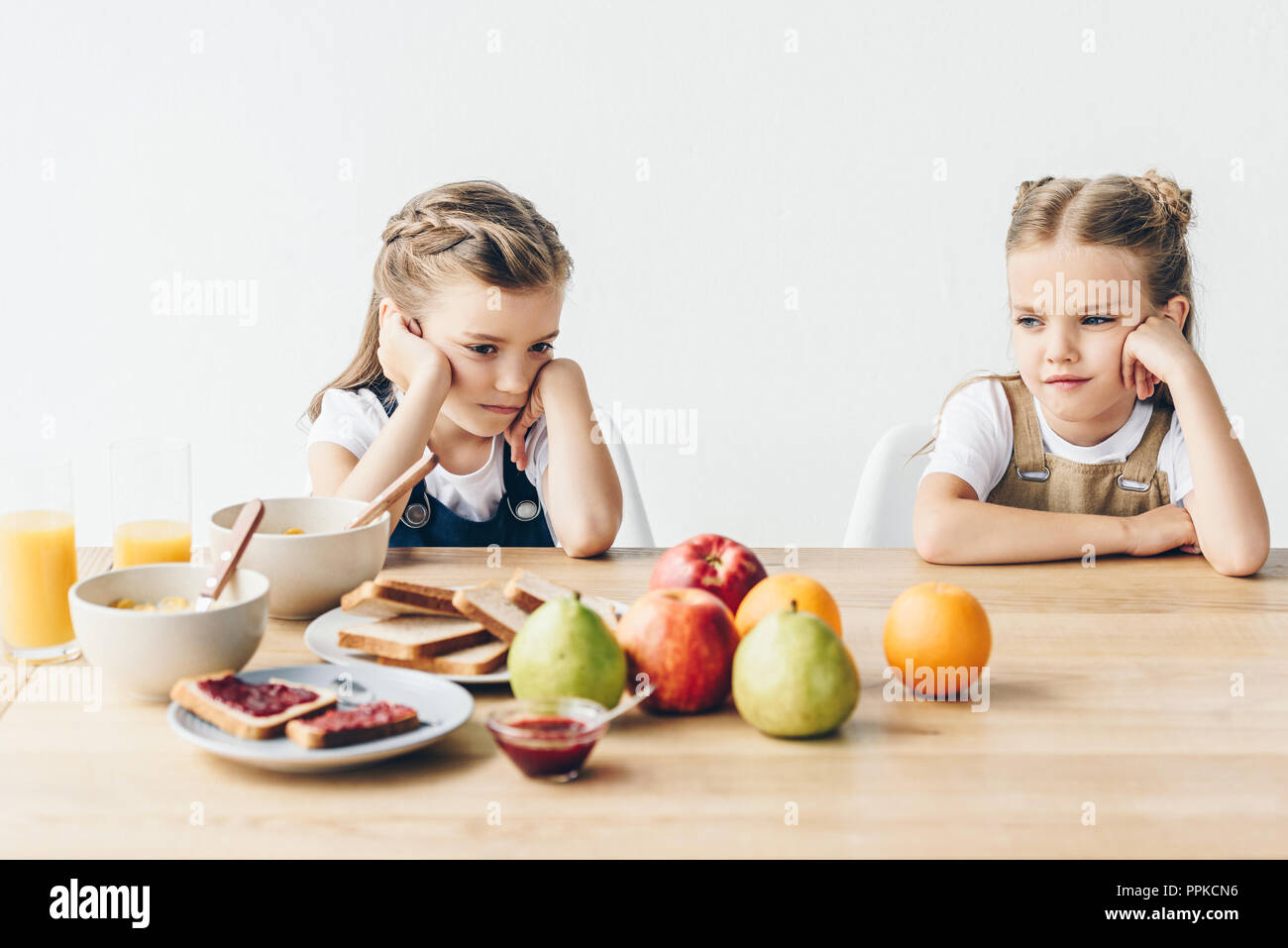 sad little sisters do not want to eat healthy breakfast isolated on ...