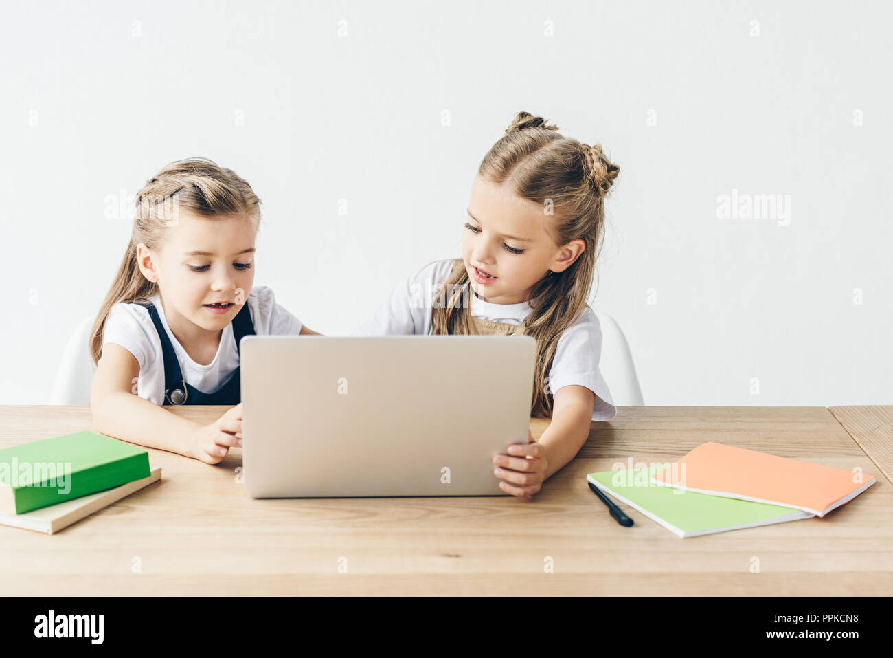 adorable little schoolgirls using laptop for studying isolated on white ...