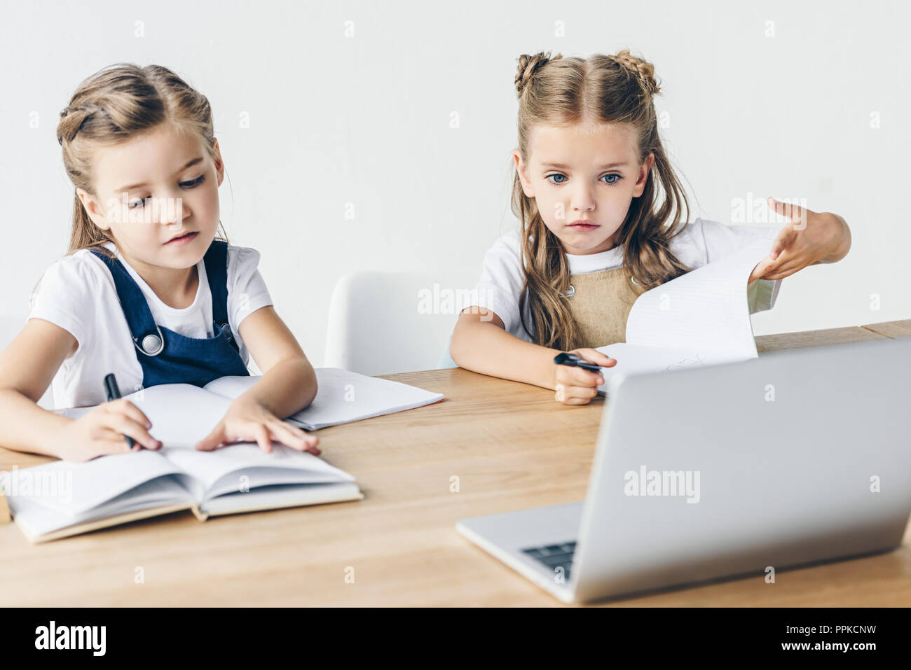 little schoolgirls studying with laptop on work desk isolated on white ...