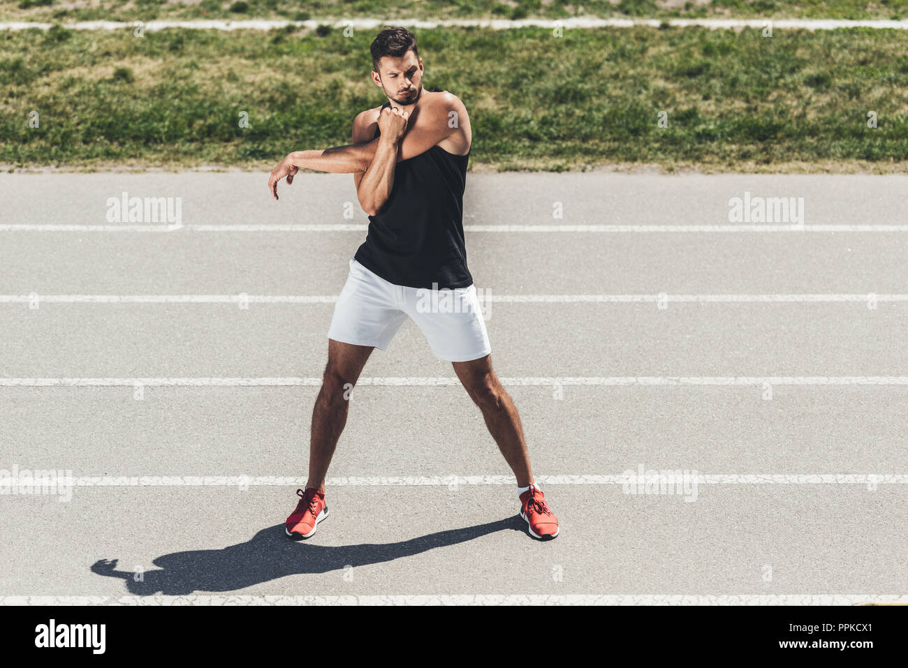 male athlete stretching on running track at sport playground Stock ...