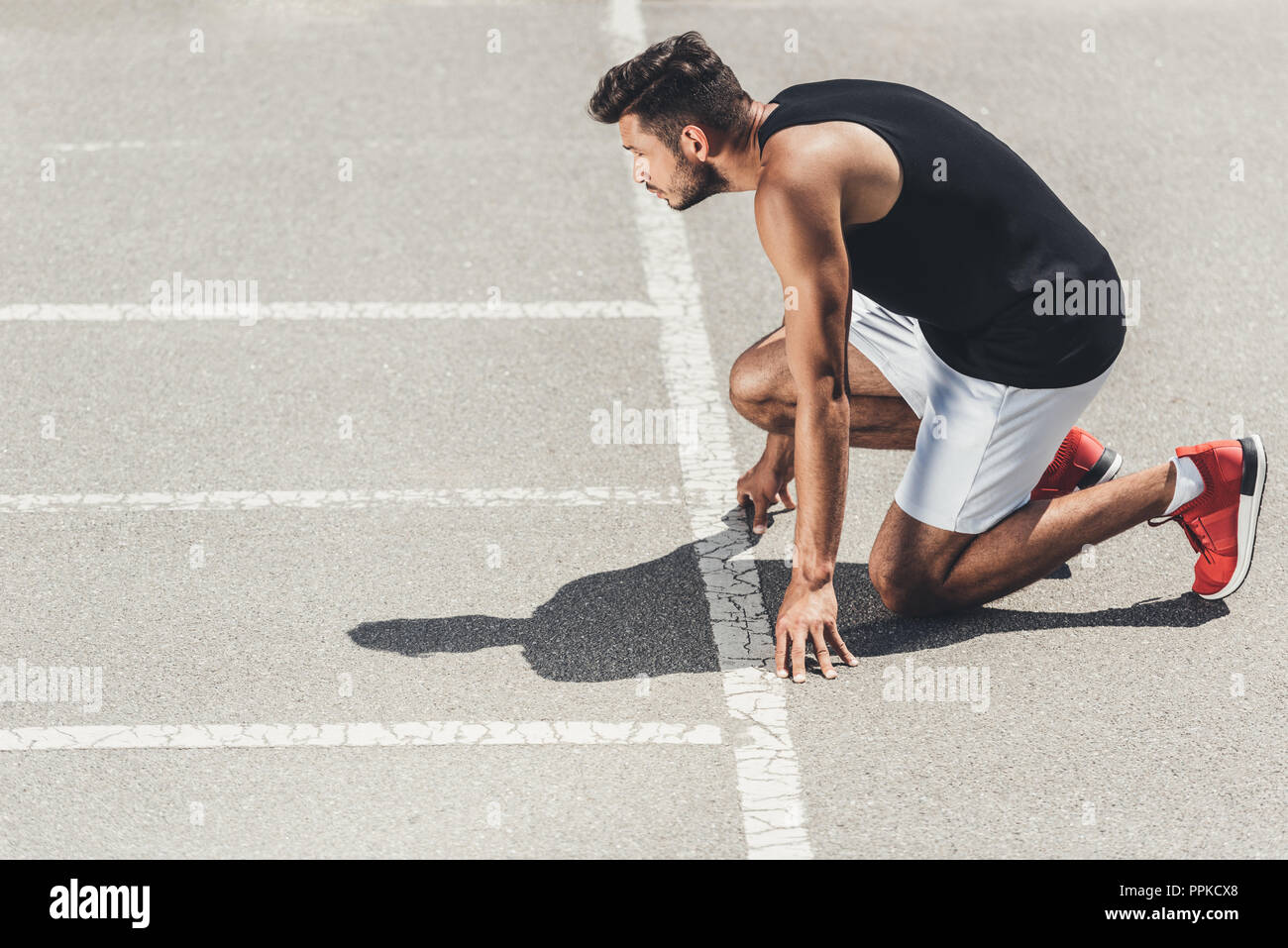 side view of young male athlete on low start on running track Stock ...