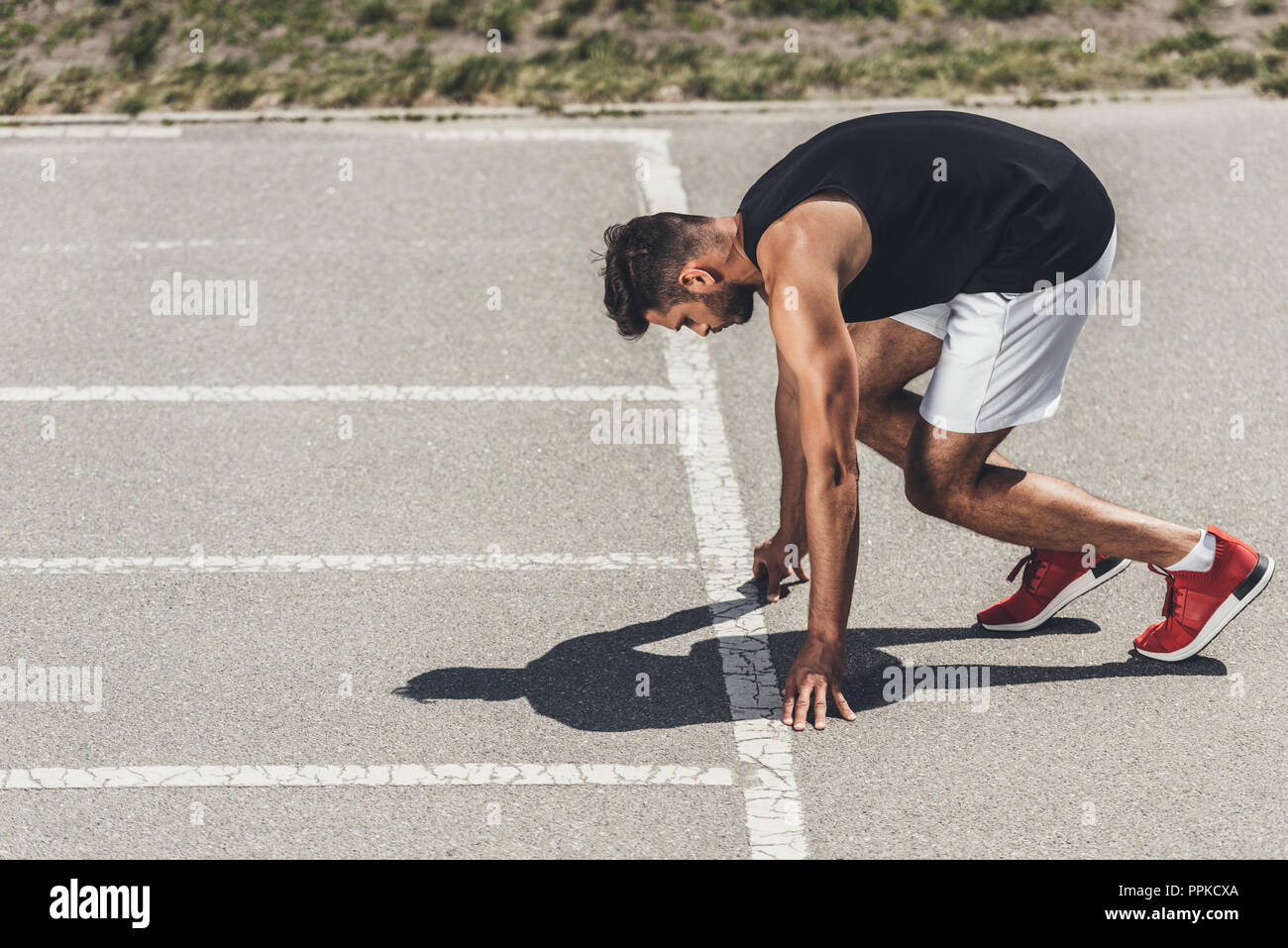serious young male athlete on low start on running track Stock Photo ...