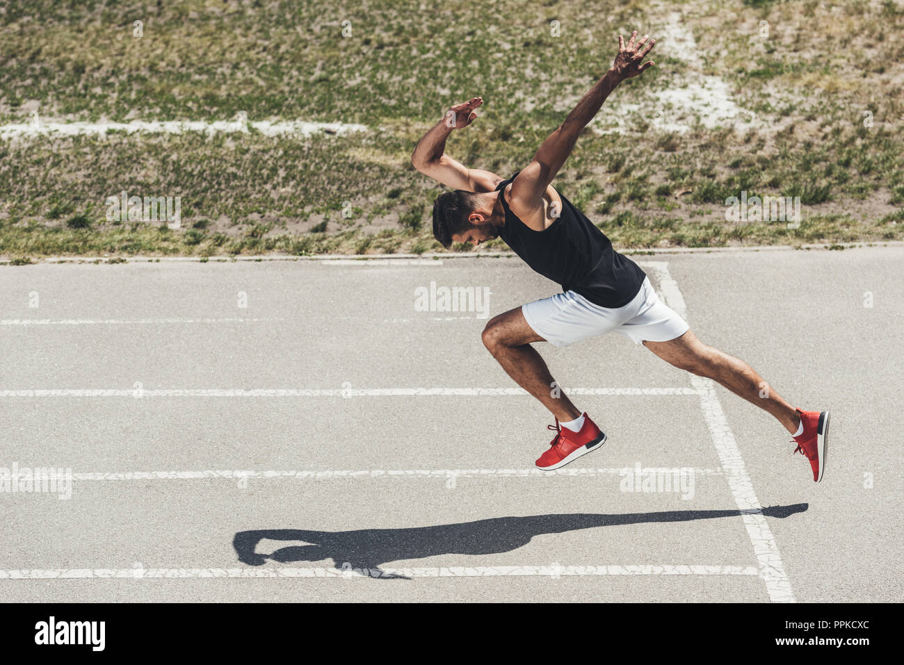 high angle view of male sprinter taking off from low start on running ...