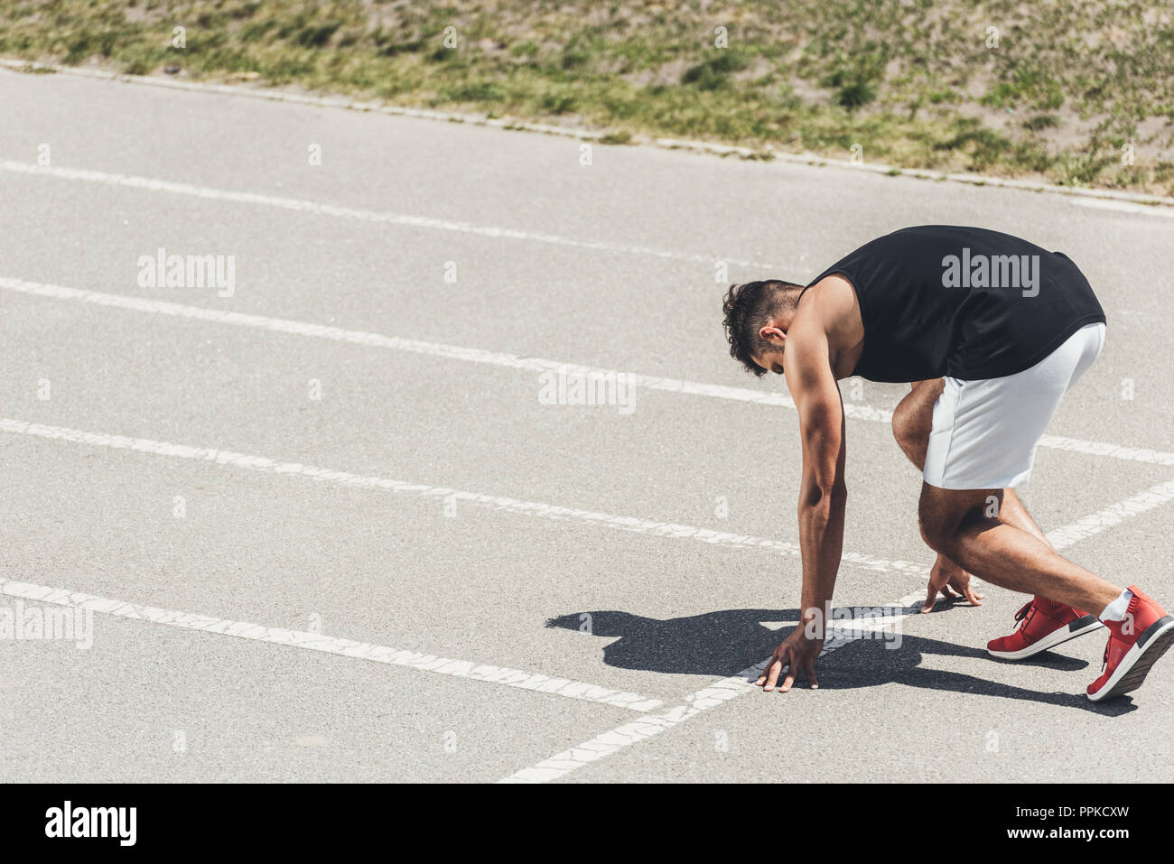 young male sprinter in starting position on running track Stock Photo ...
