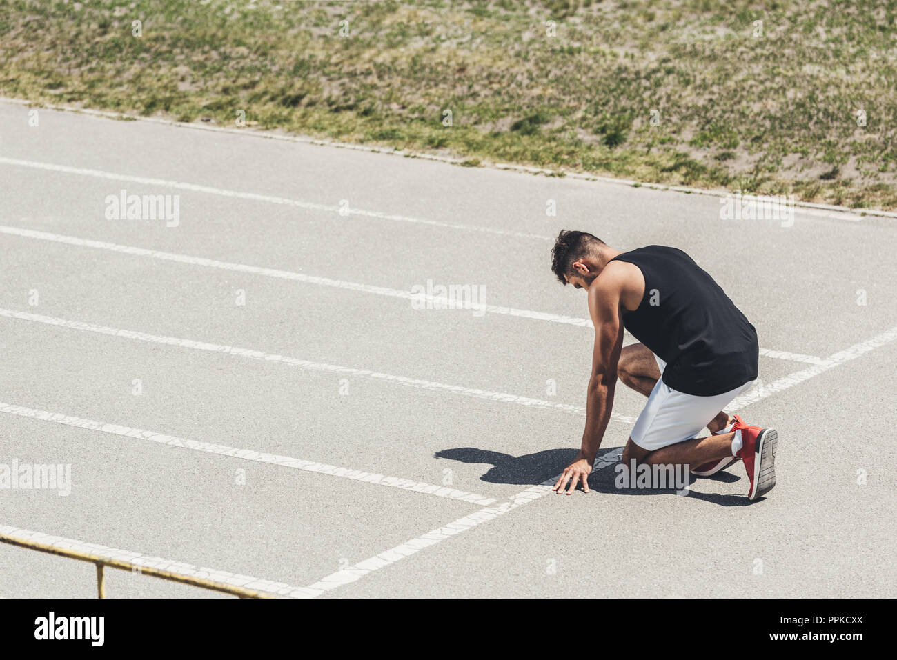 side view of male sprinter in starting position on running track Stock ...