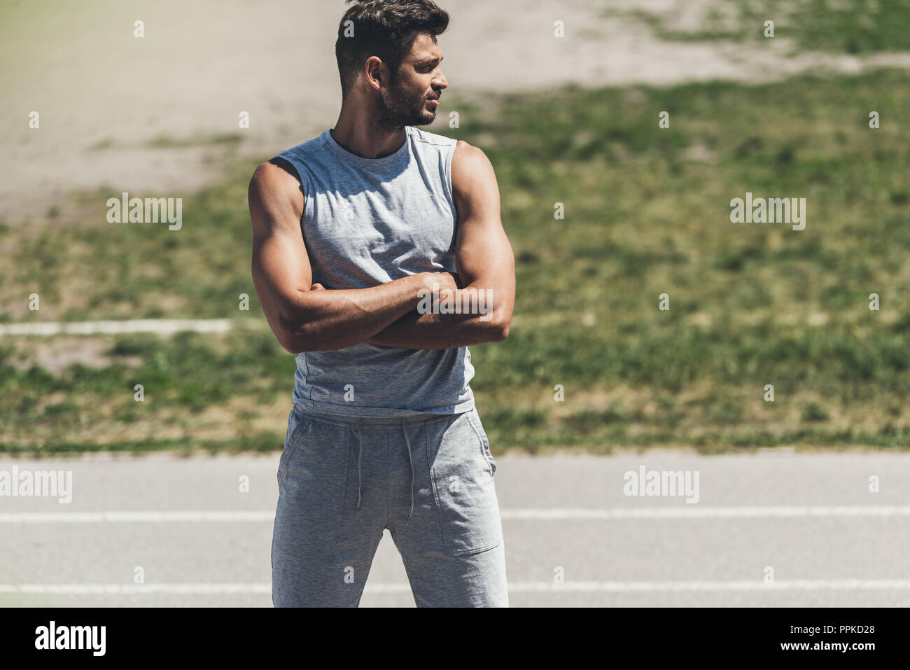 muscular young man with crossed arms on running track Stock Photo - Alamy