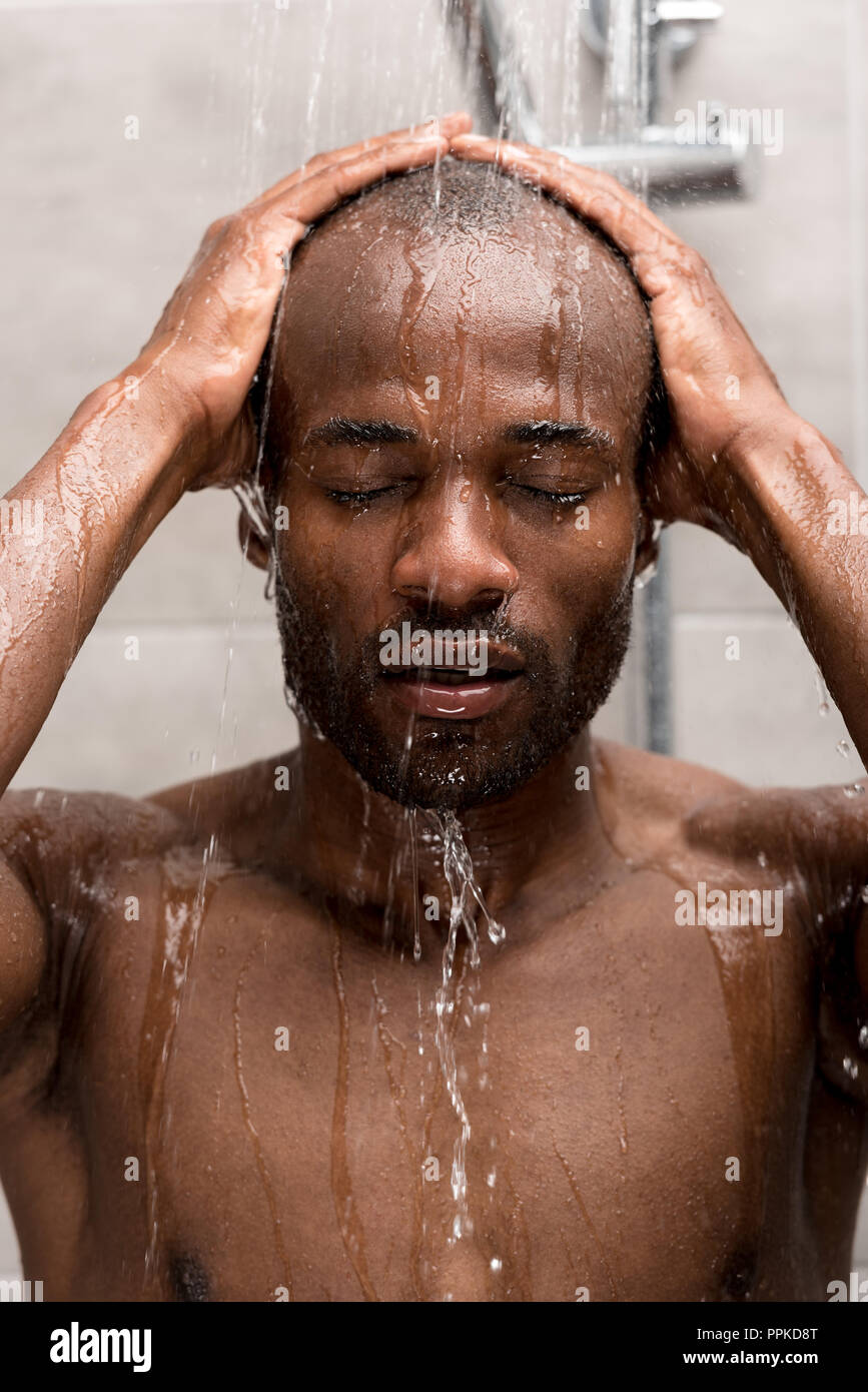 handsome young african american man washing in shower with closed eyes ...