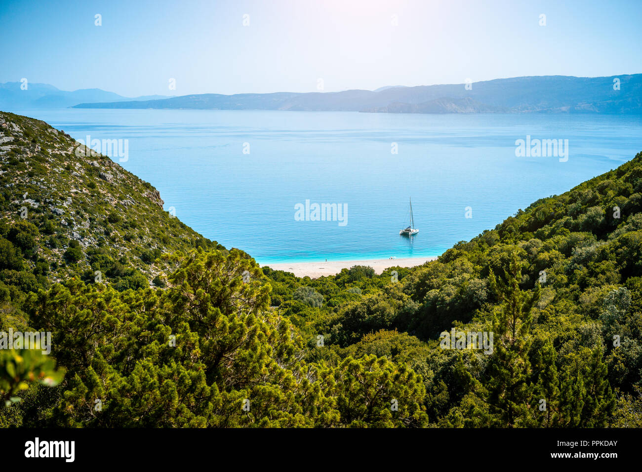 Stunning view of Fteri beach with white sailboat in hidden bay ...