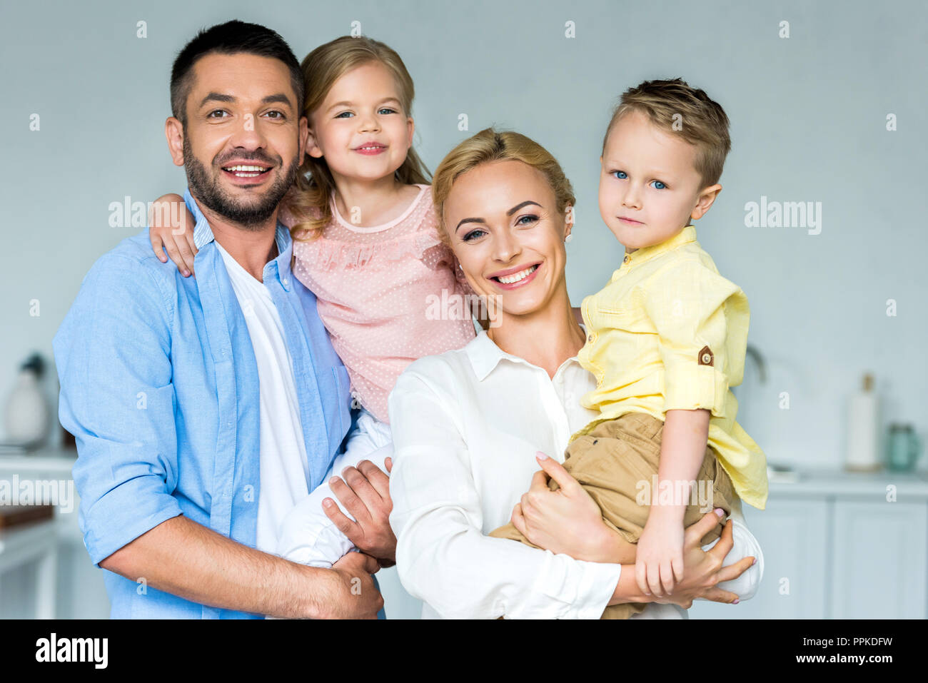 happy family with two adorable kids smiling at camera together at home ...
