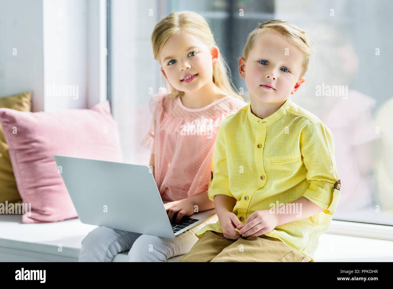 adorable kids using laptop and smiling at camera at home Stock Photo ...