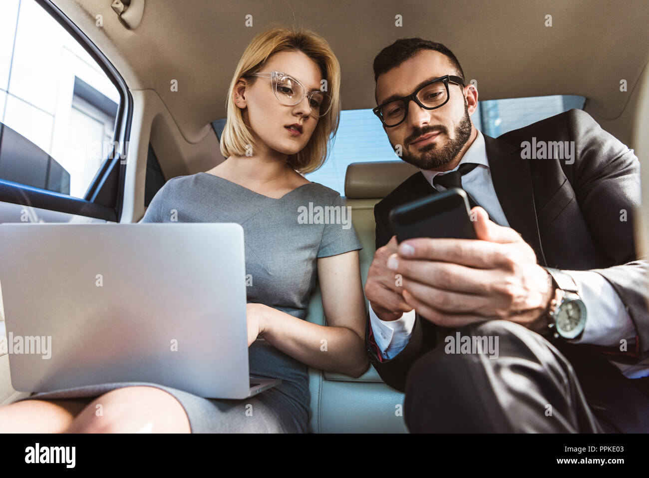 low angle view of handsome businessman showing something on smartphone ...