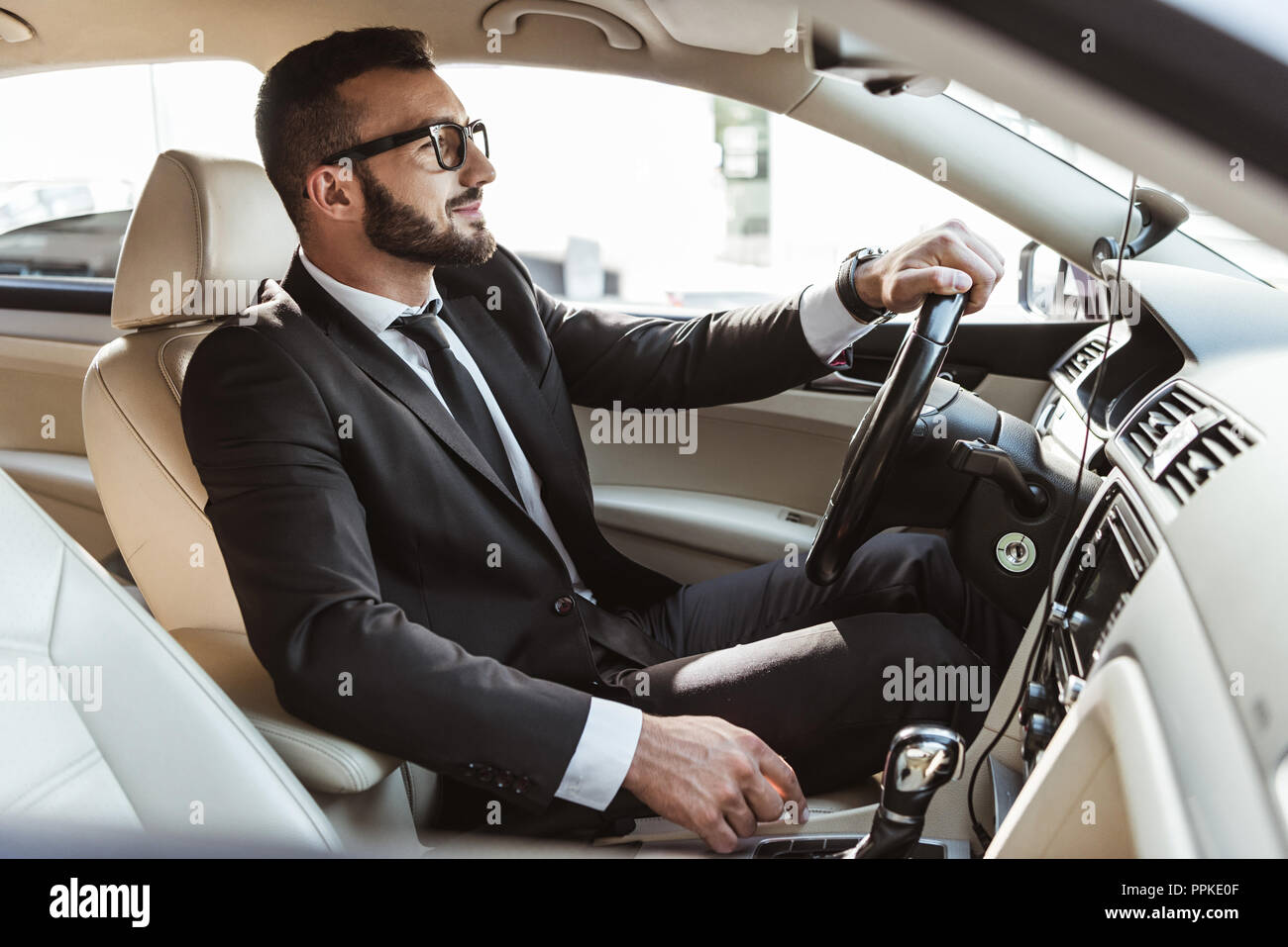 side view of handsome driver in suit driving car Stock Photo - Alamy