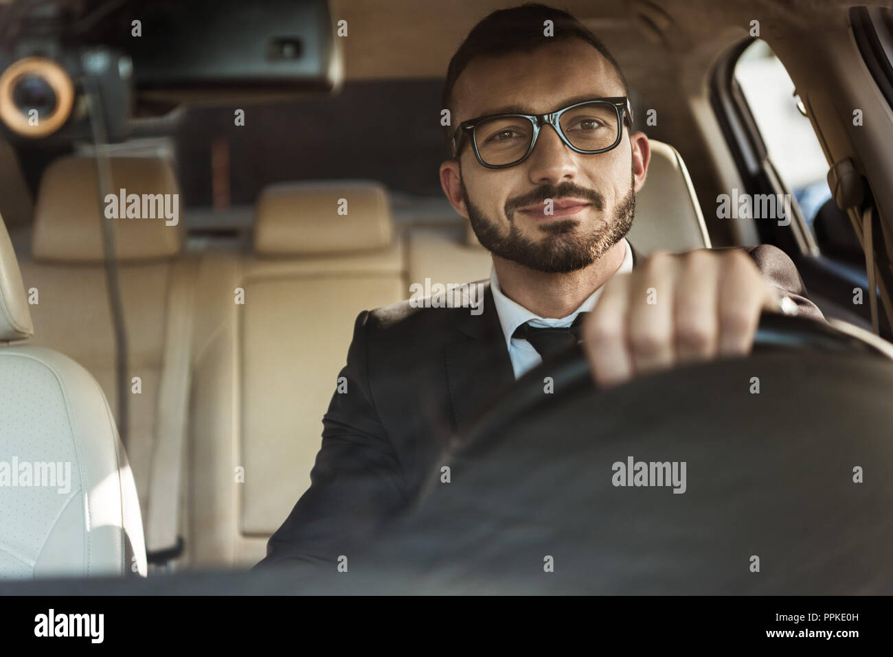 handsome cheerful driver in suit driving car Stock Photo - Alamy