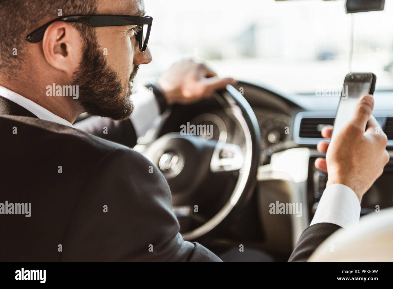 handsome driver in suit driving car and holding smartphone Stock Photo ...