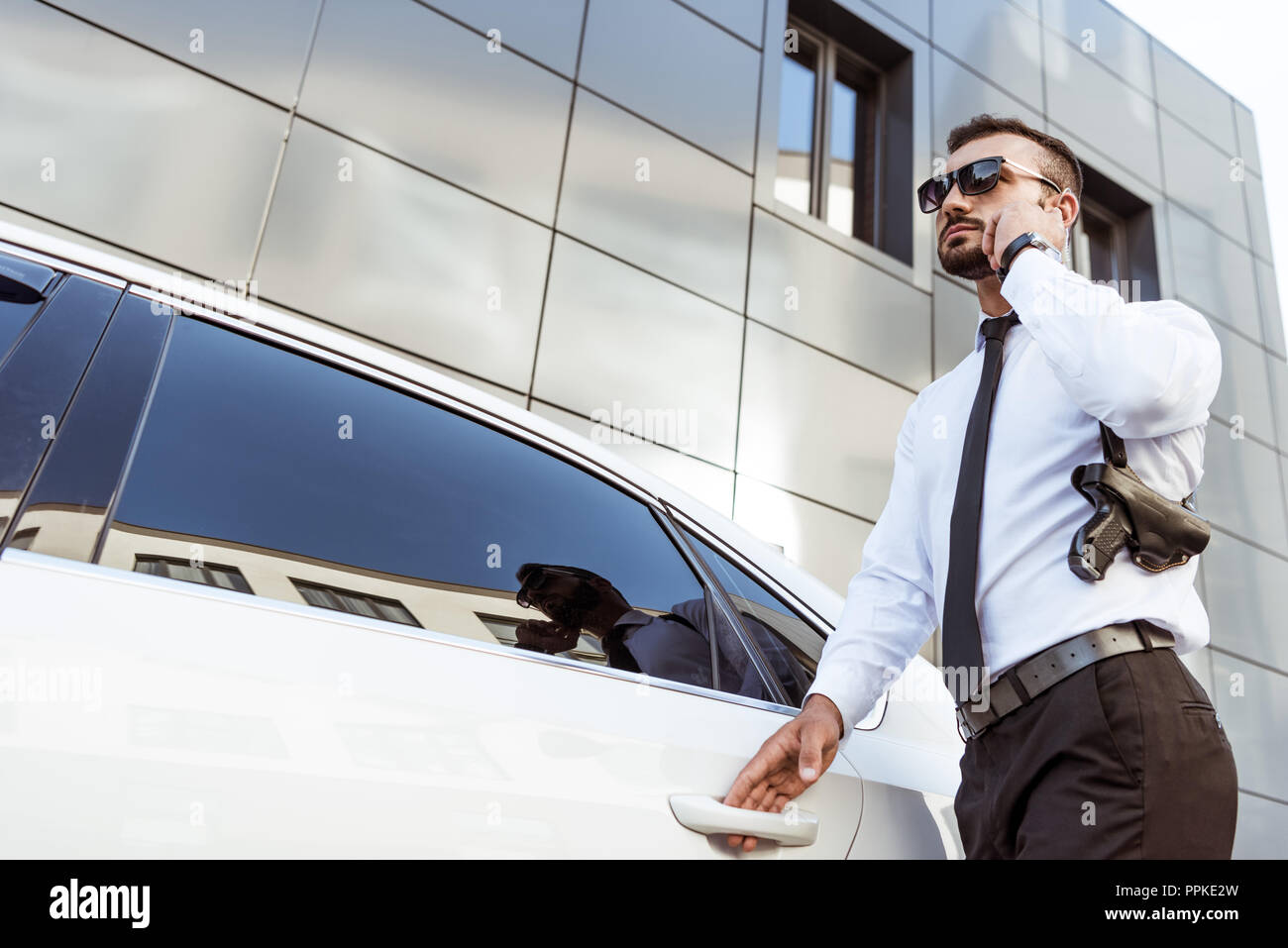 low angle view of handsome security guard listening message with ...