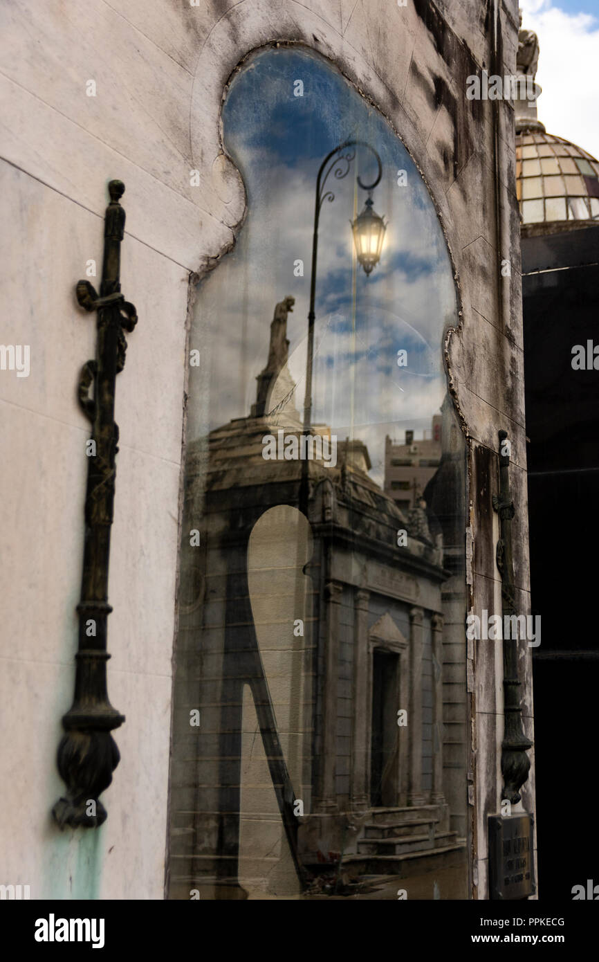 Reflection of the sky and a family vault in a glass window in the ...