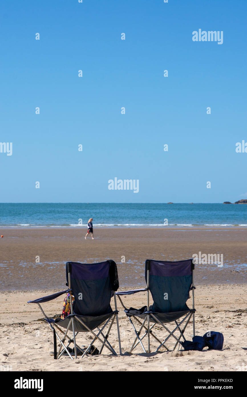 Two collapsible chairs on a beach in Anglesey, Wales Stock Photo - Alamy