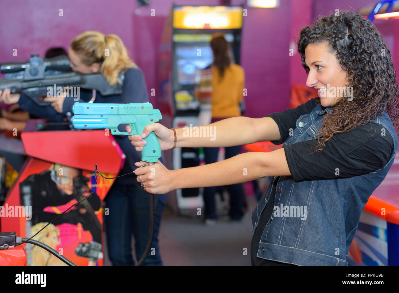 Woman firing gun on arcade game Stock Photo - Alamy