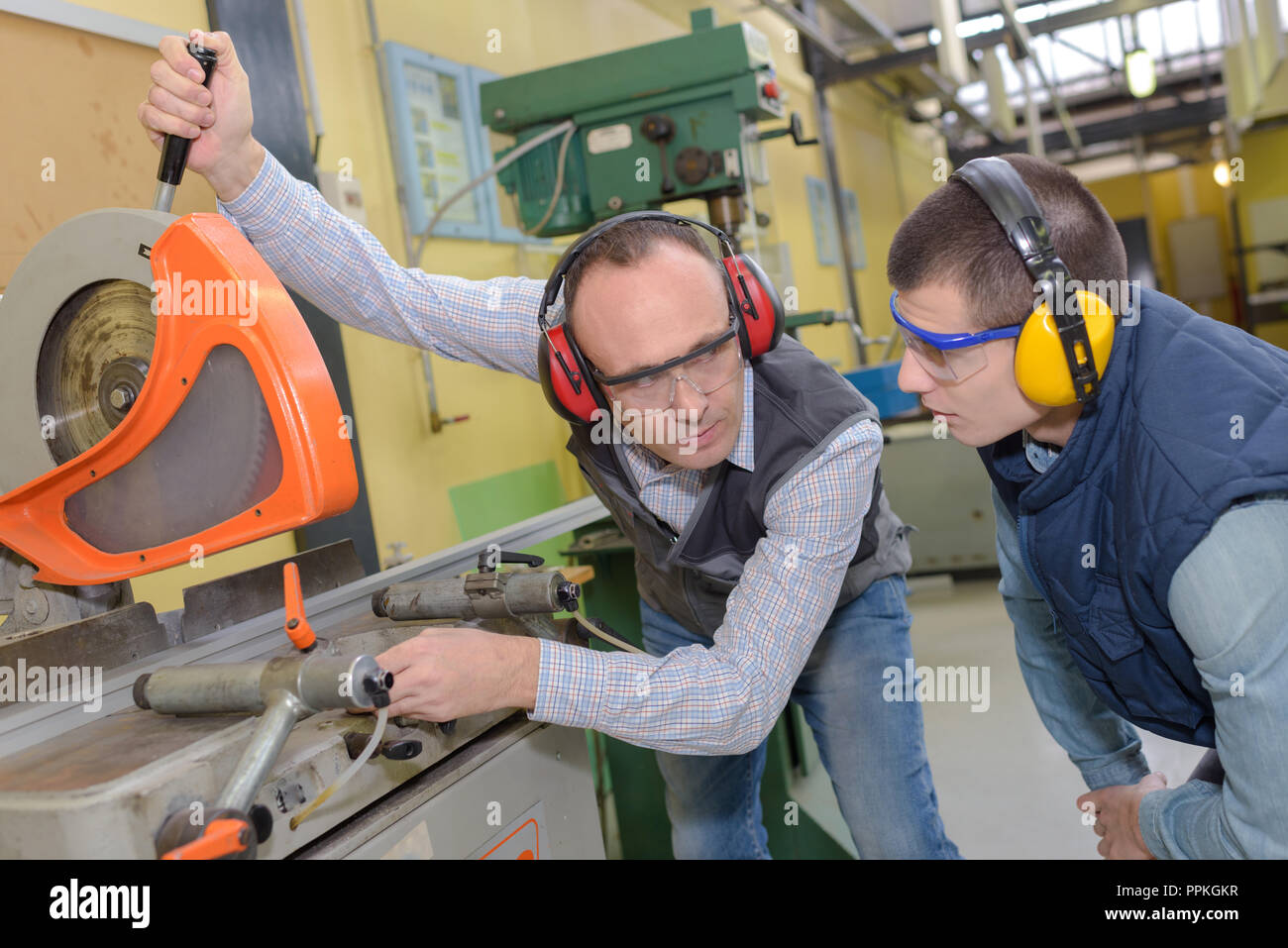 engineer and apprentice using machinery in factory Stock Photo - Alamy