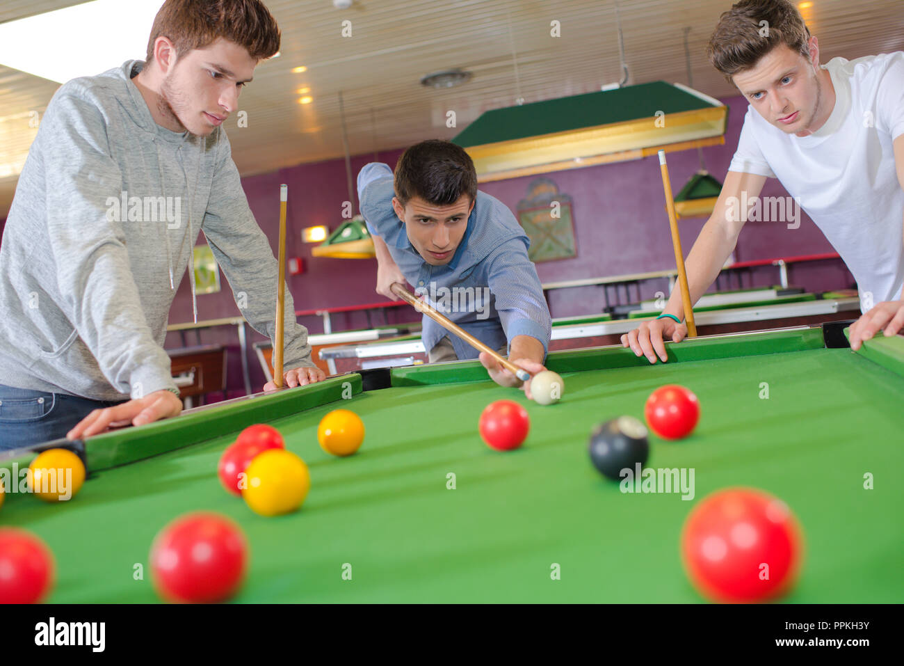 Three friends playing pool Stock Photo - Alamy
