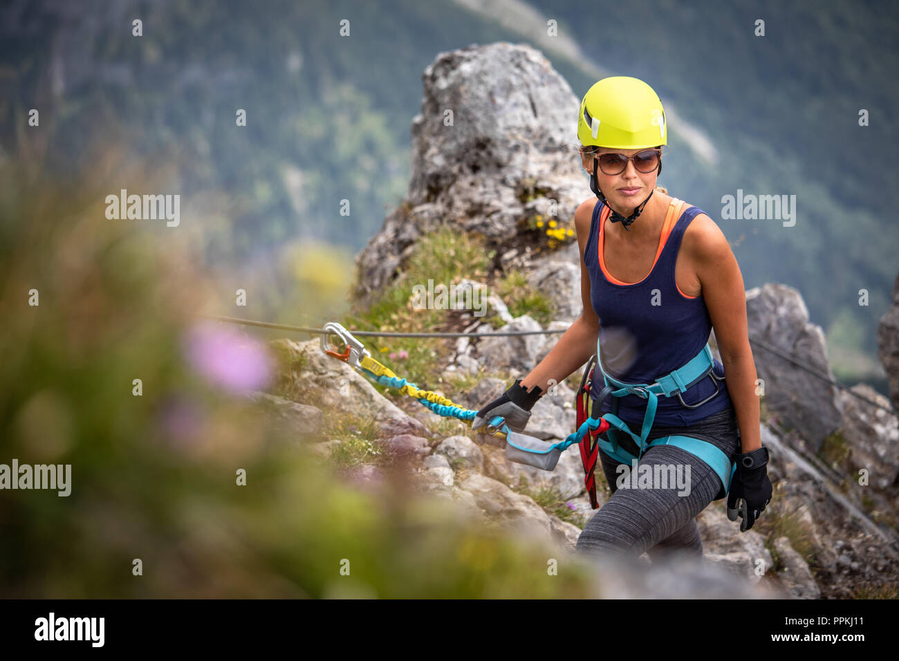 Pretty, female climber on a via ferrata - climbing on a rock in Swiss ...