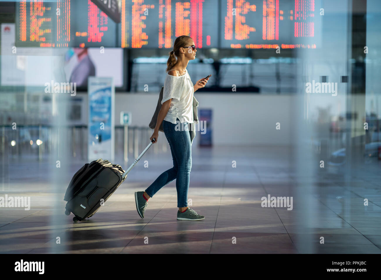 Young woman with her luggage at an international airport, before going ...