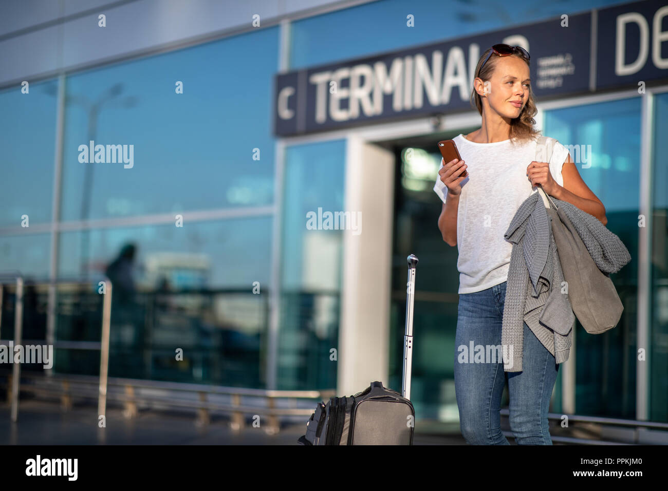 Young woman with her luggage at an international airport, before going ...
