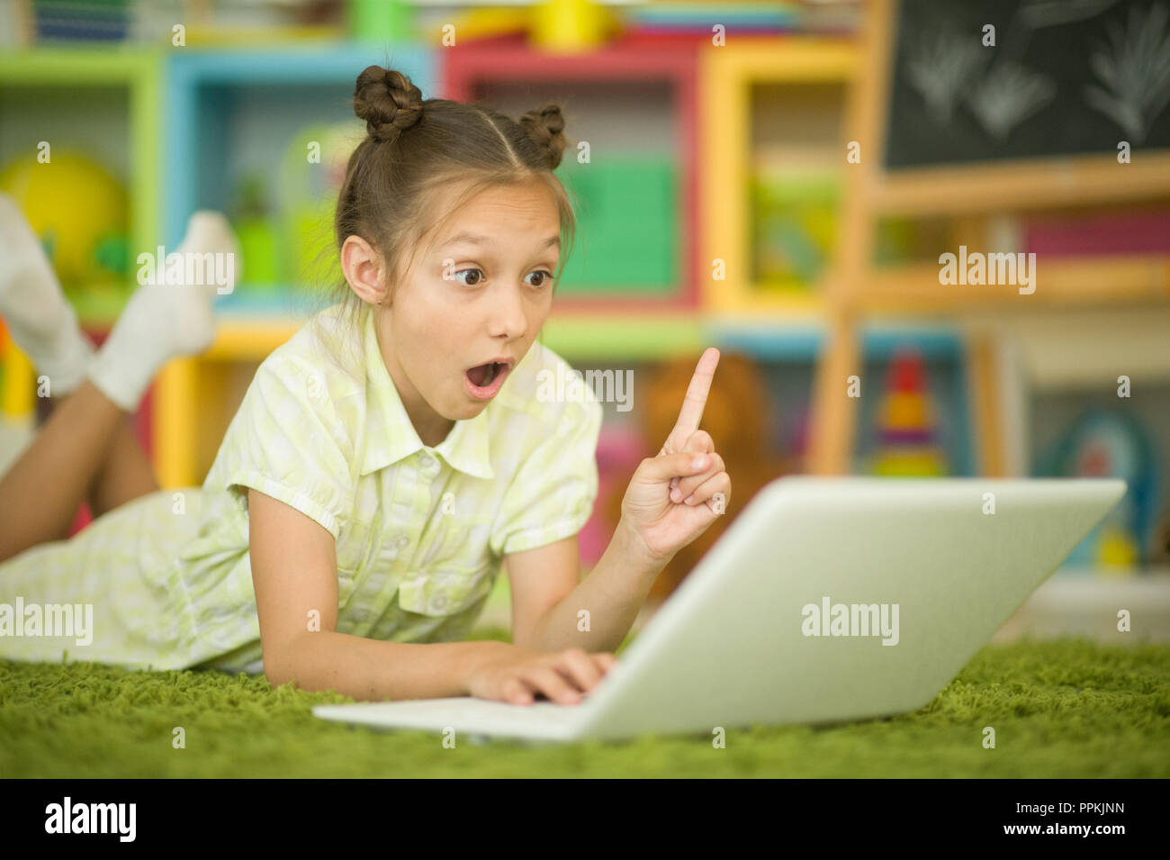 Cute girl using laptop and pointing up Stock Photo - Alamy