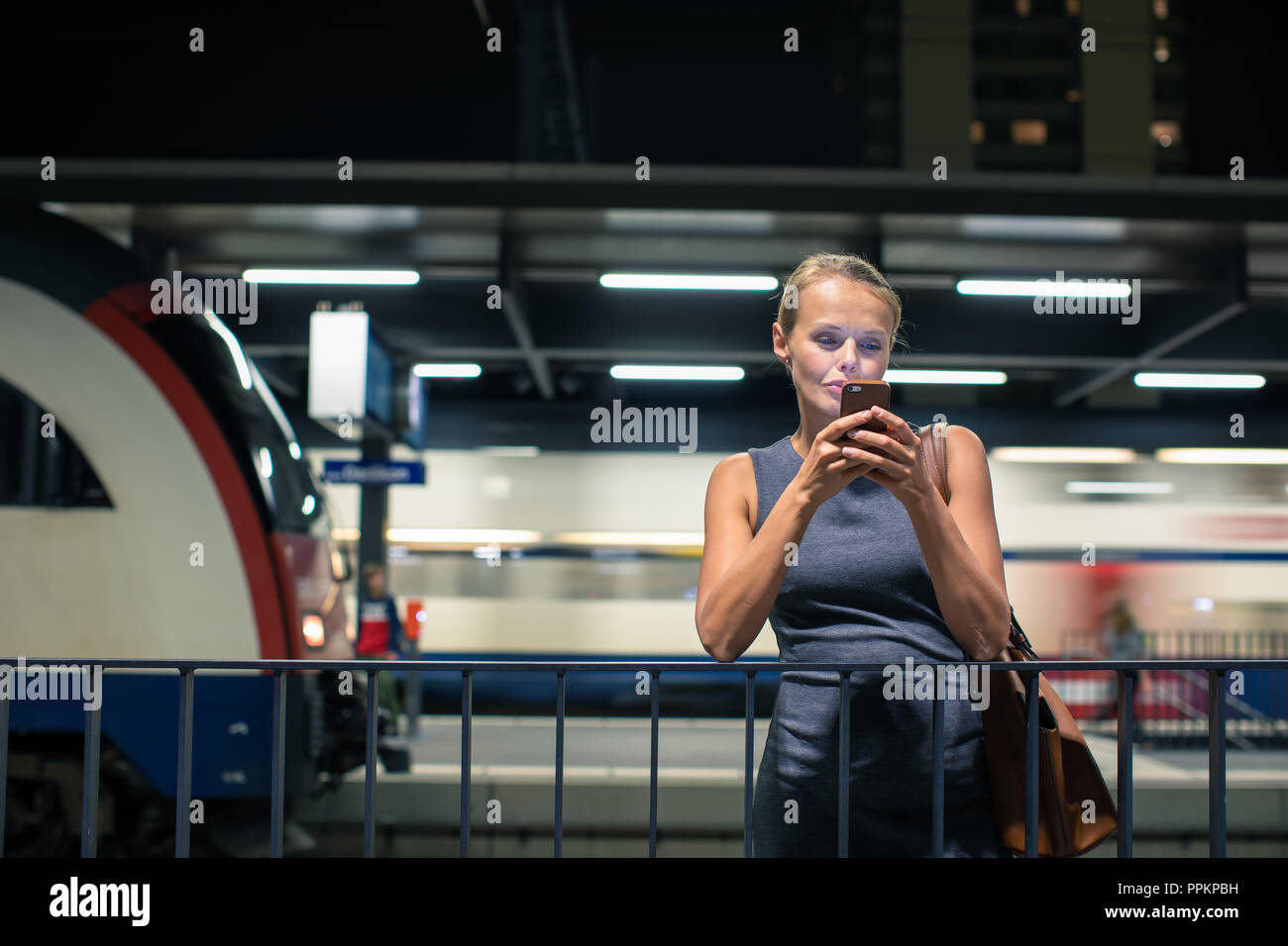 Pretty, young female commuter waiting for her daily train in a modern ...