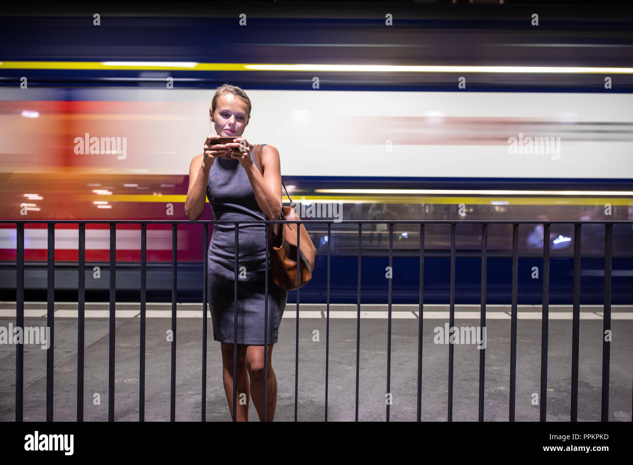 Pretty, young female commuter waiting for her daily train in a modern ...