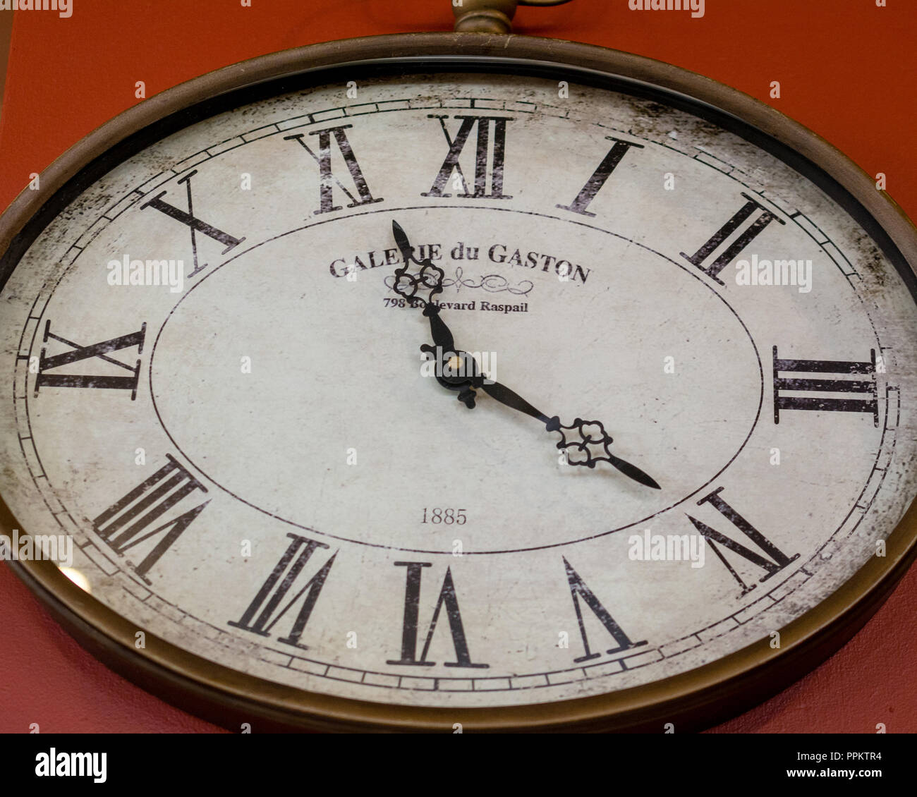 1885 Galerie du Gaston Oval Wall Clock on a red wall, marking eleven ...