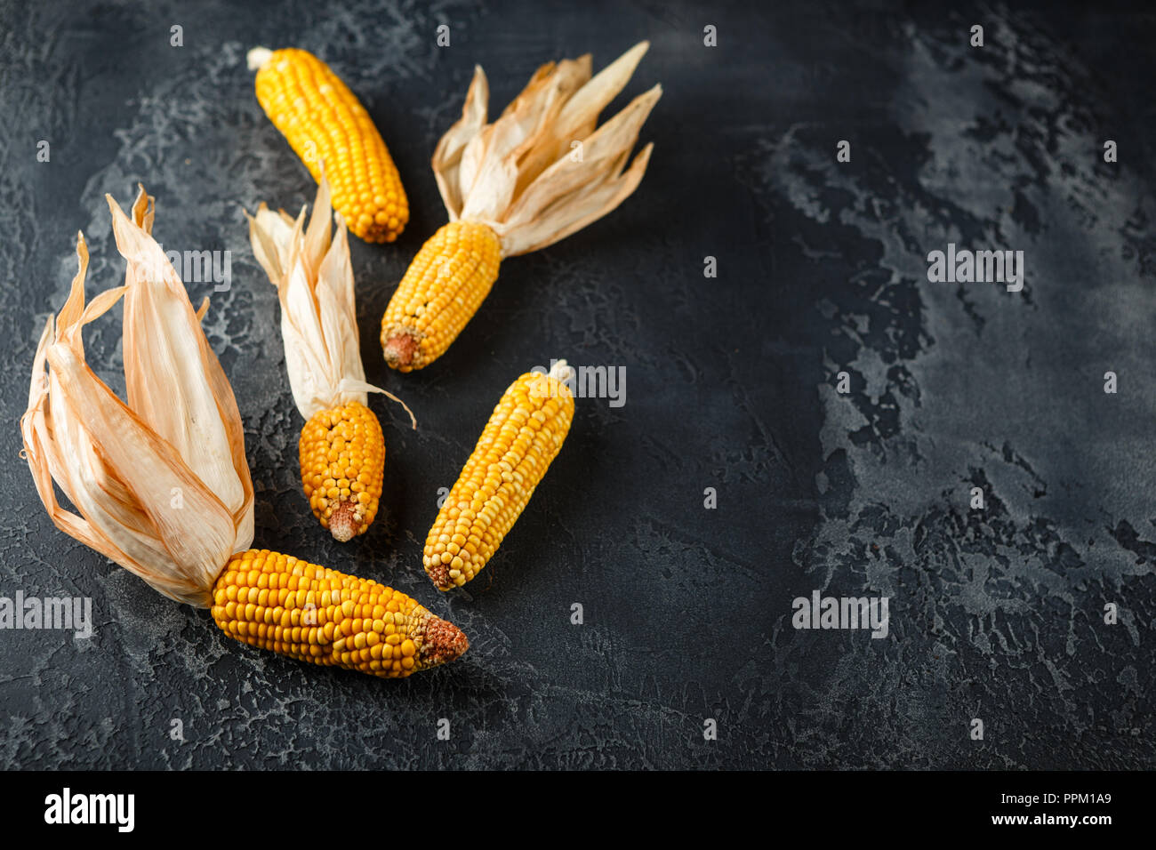 Three small cobs of corn on a black background Stock Photo - Alamy