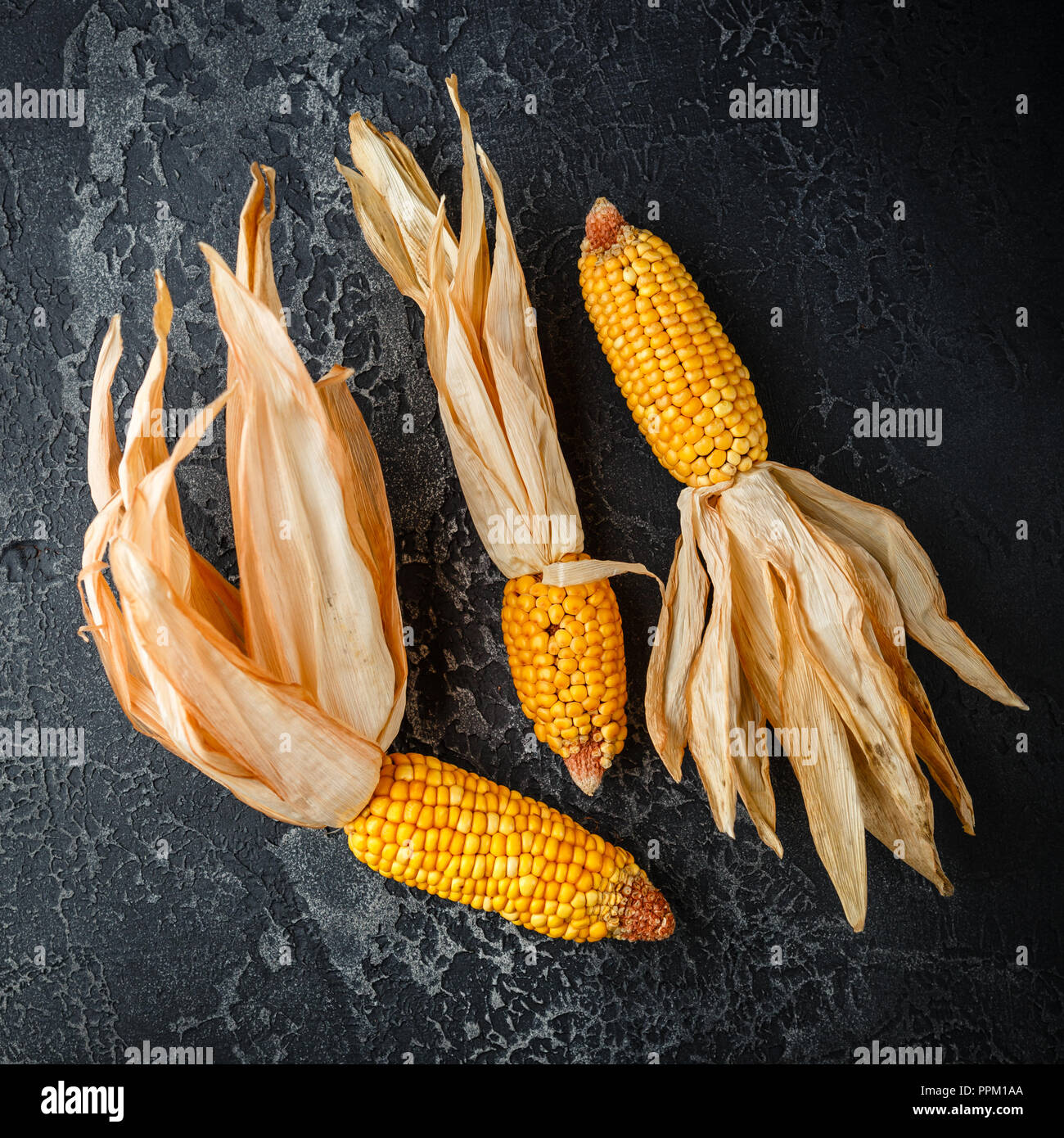 Three small cobs of corn on a black background Stock Photo - Alamy