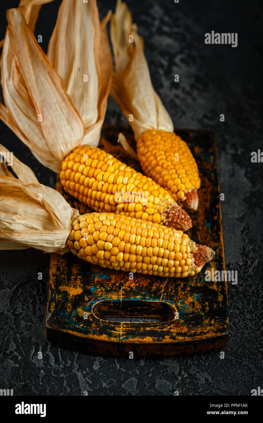 Three small cobs of corn on a black background Stock Photo - Alamy