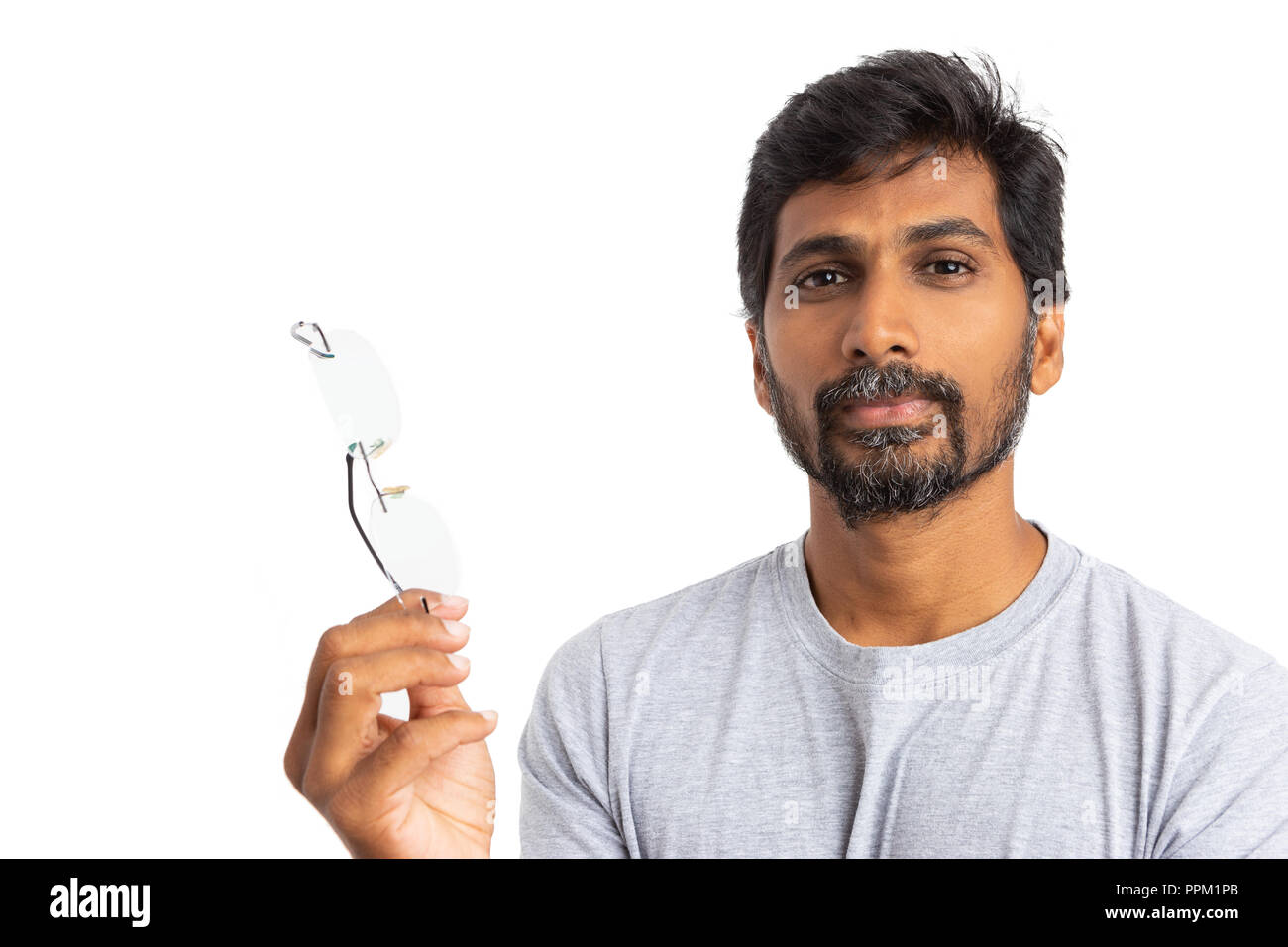 Indian man with sceptical expression gesturing with eyeglasses or ...