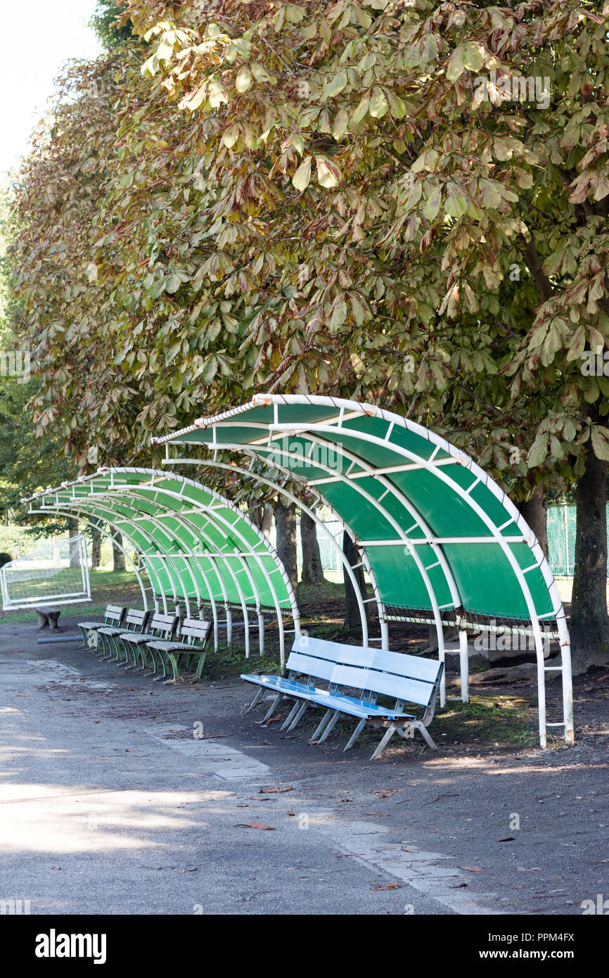 Blue plastic bench with retro vinyl green roof in park in early autumn ...