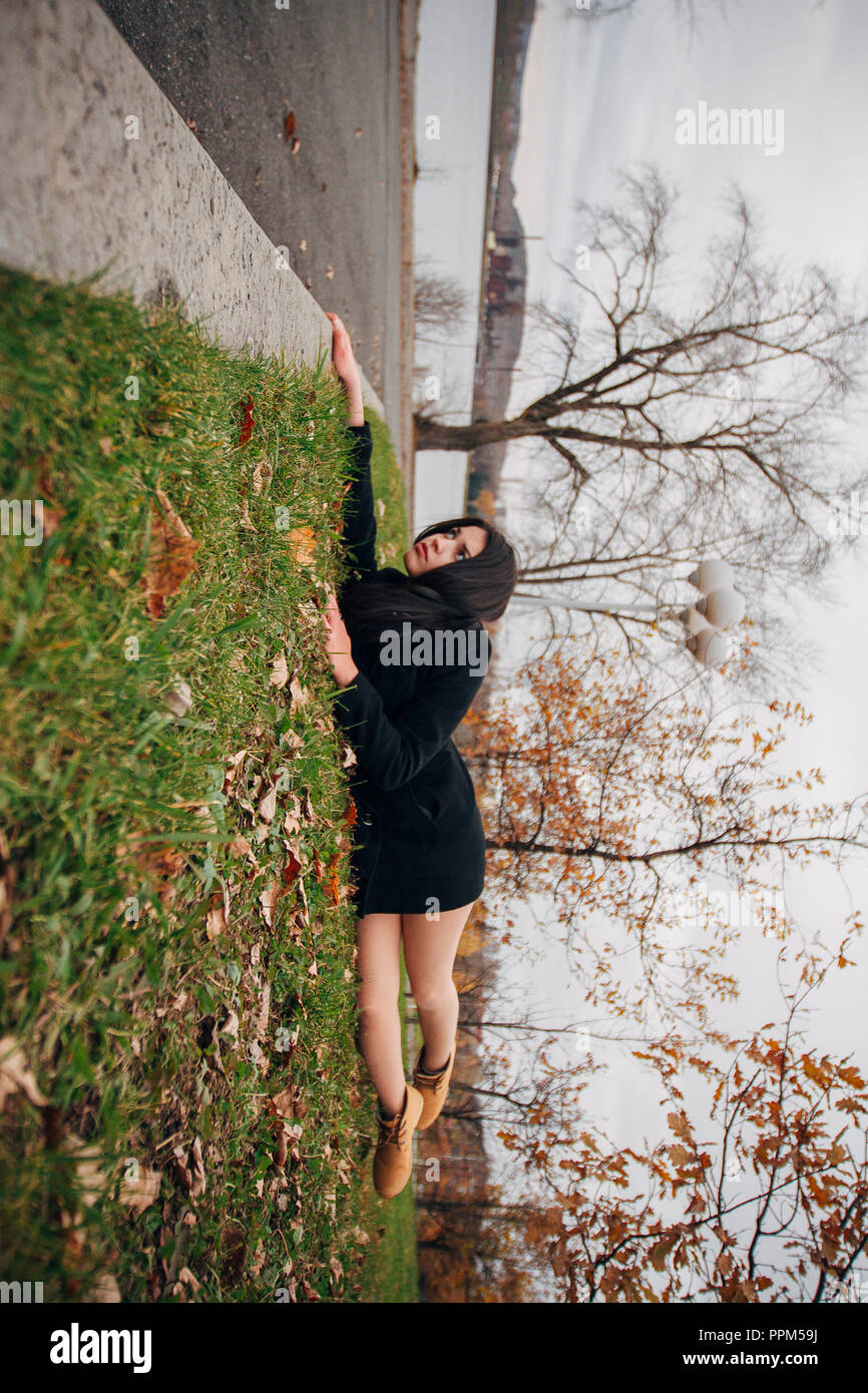 Creative photo of a brunette girl in autumn Park. Woman hanging from ...