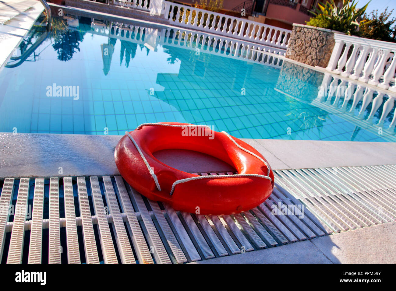 Red lifebuoy pool ring at swimming pool. Red pool ring in cool blue ...