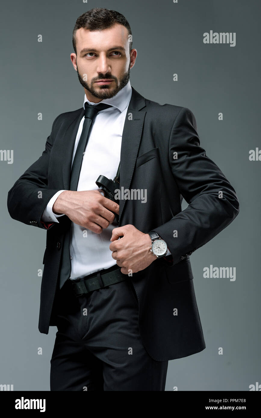handsome security guard taking gun isolated on grey Stock Photo - Alamy