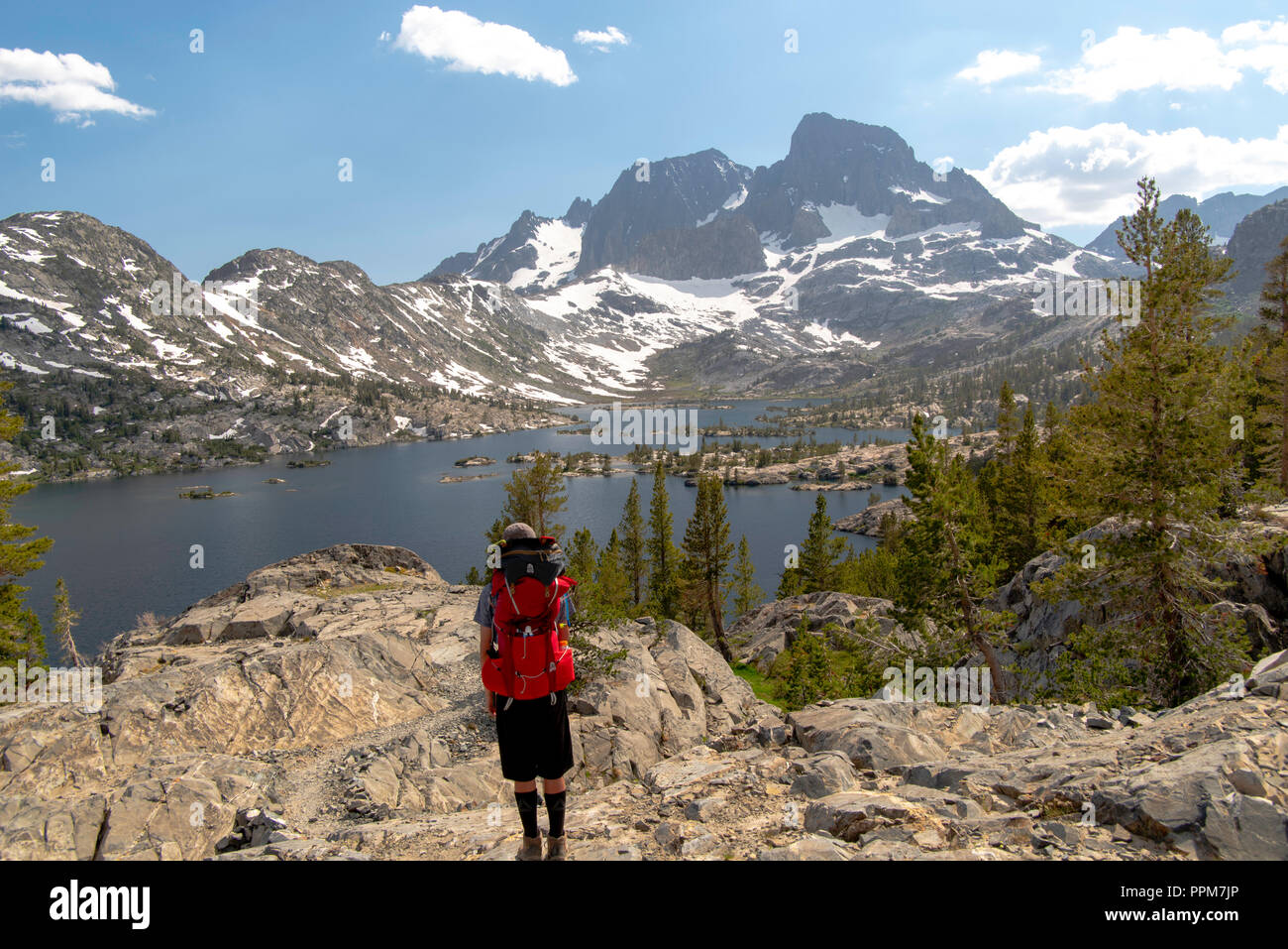 A backpacker soaks in the view of Garnet Lake with Banner Peak in the ...