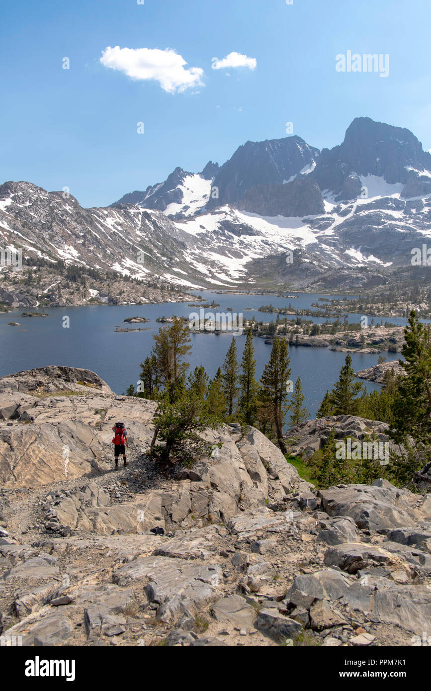 A backpacker approaches Garnet Lake with Banner Peak in the background ...