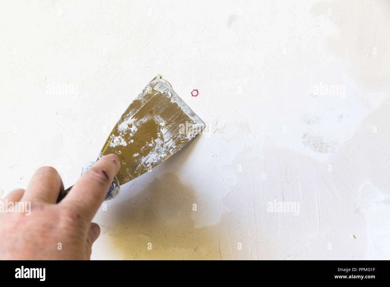 Close-up of a woman hand with old metal spatula to put plaster filler ...
