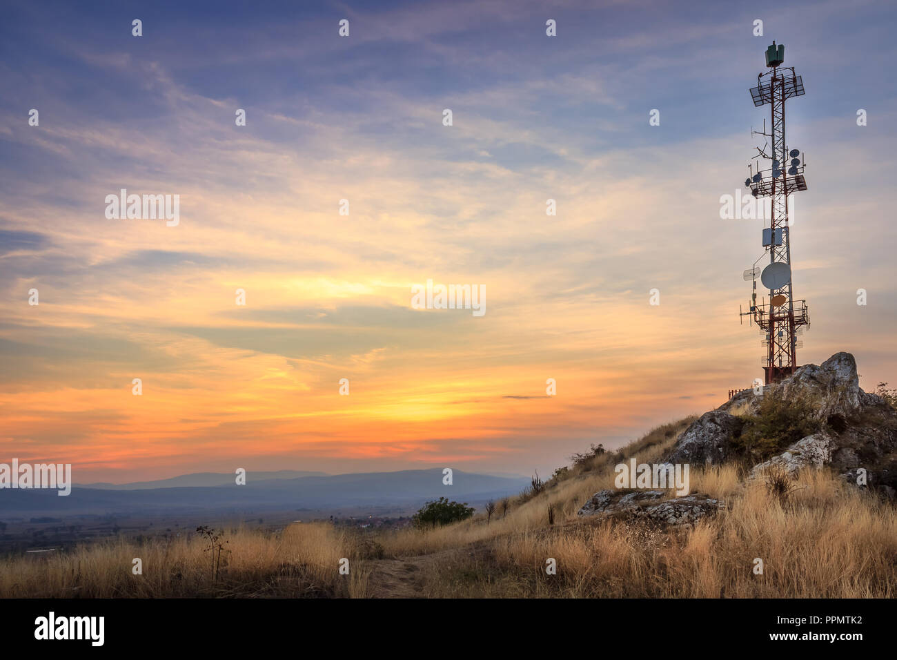 Radio tower with antennas on a summit during dramatic, colorful sunset ...
