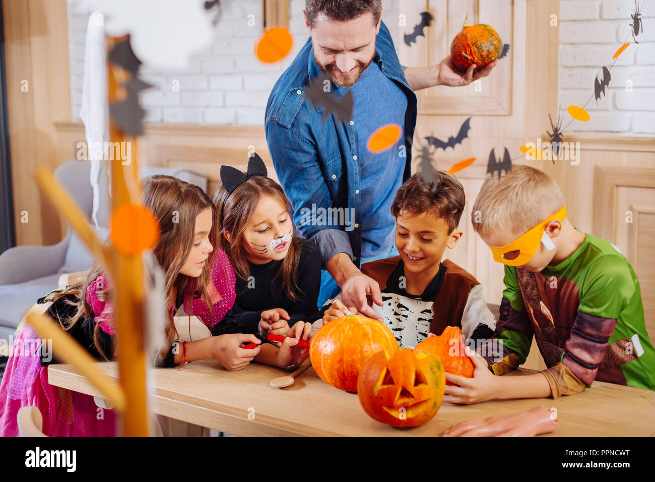 Bearded handsome event manager helping children wearing Halloween ...