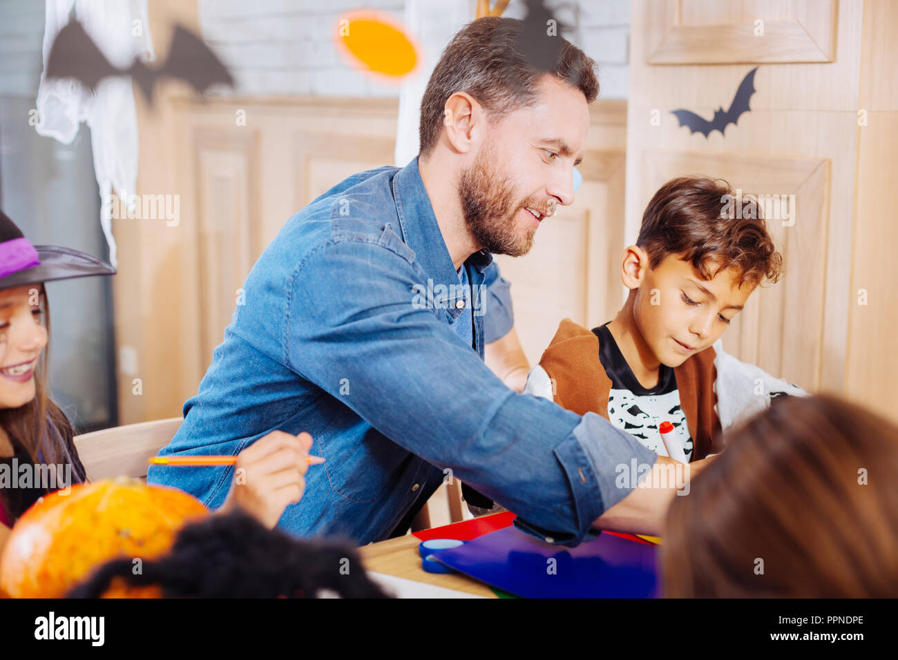 Helpful father feeling happy celebrating Halloween with his children ...