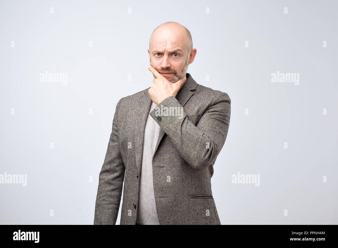 Closeup portrait of a man holding chin on hand, staring thoughtfully at ...