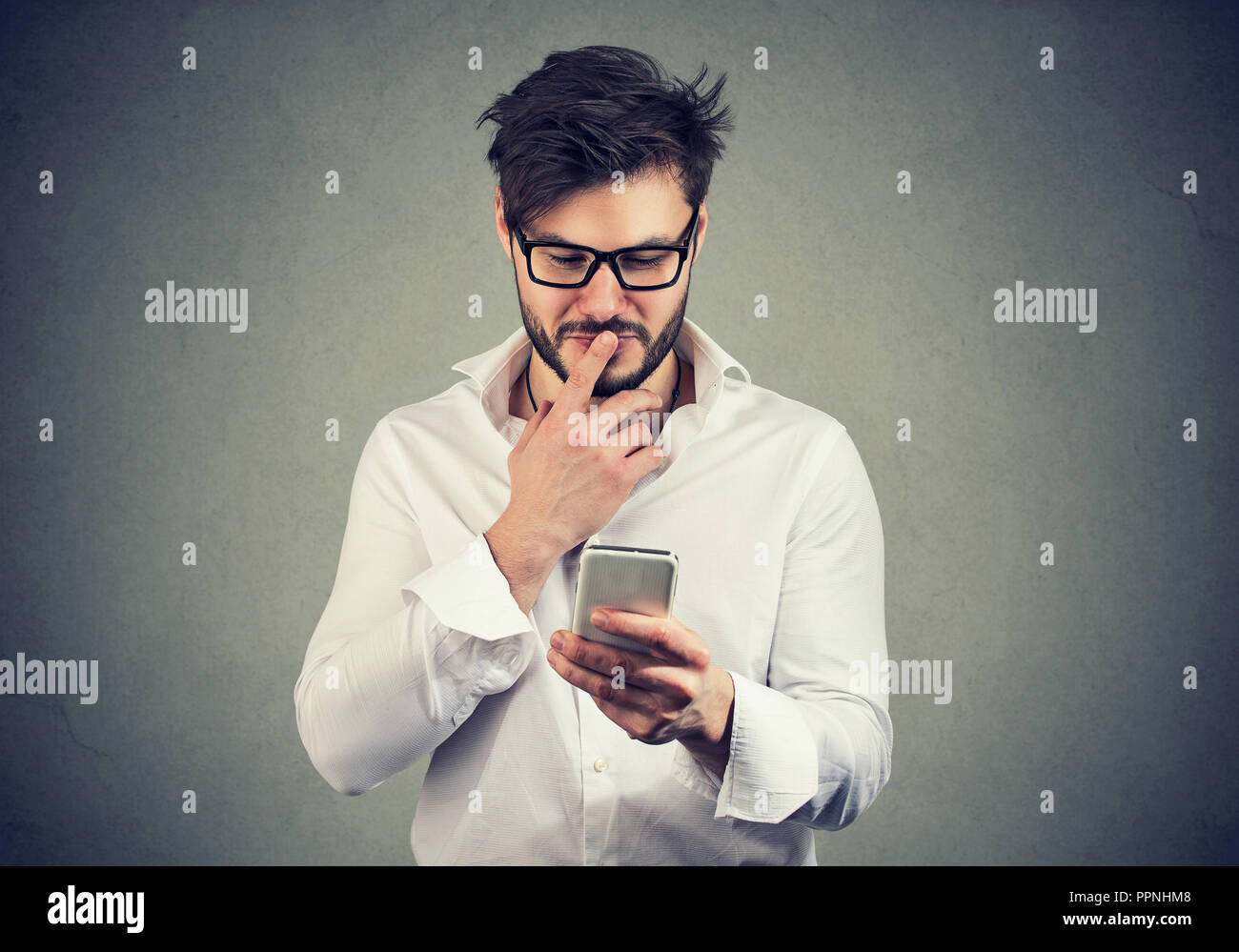 puzzled man thinking what to reply to received text message on cell ...