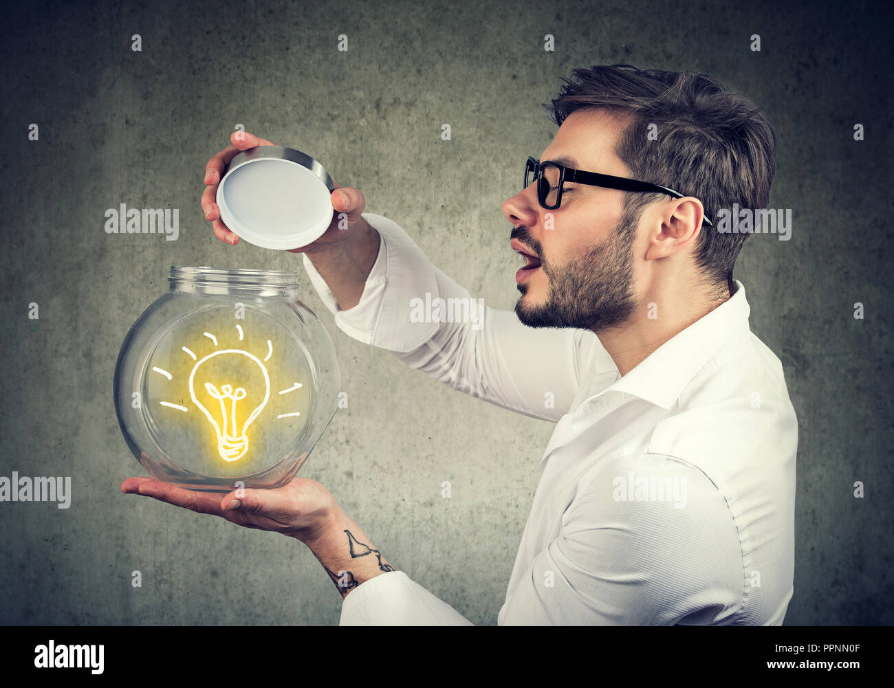 Excited man holding opening a glass jar with bright idea lighbulb ...